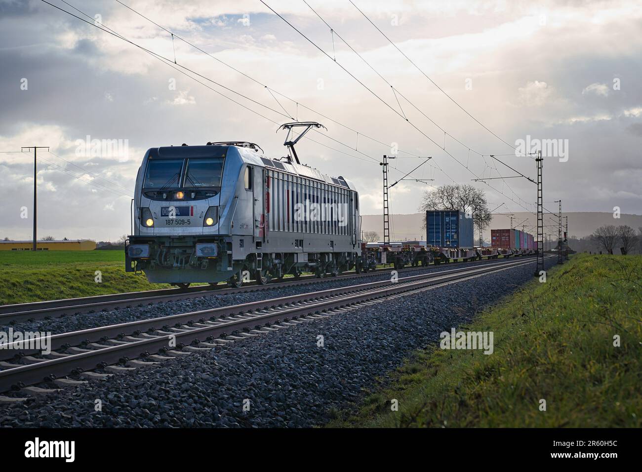 A vintage train moves along the tracks in a landscape, with lush green ...
