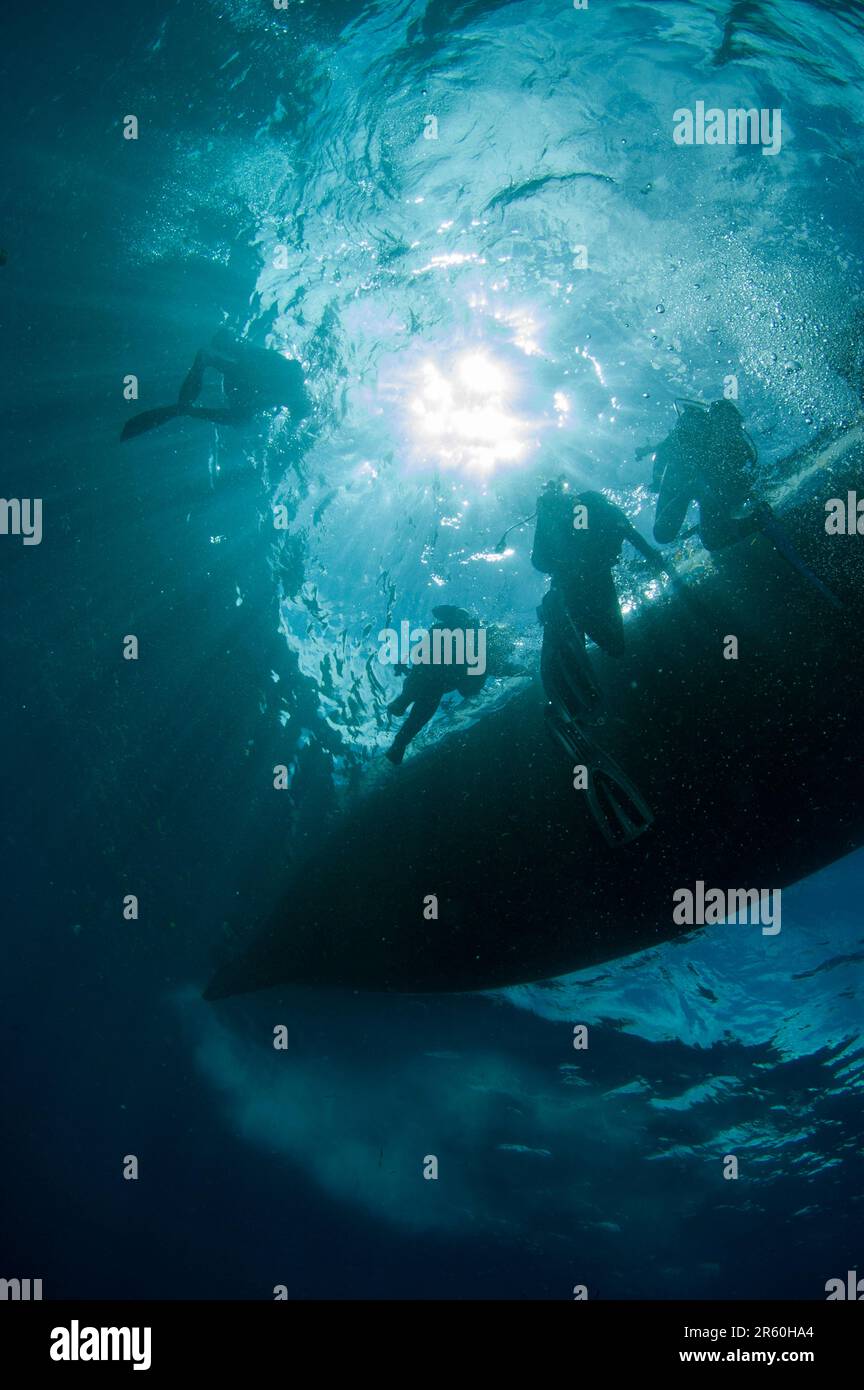 Divers getting into dive boat with sun in background, Dante's Wall dive ...