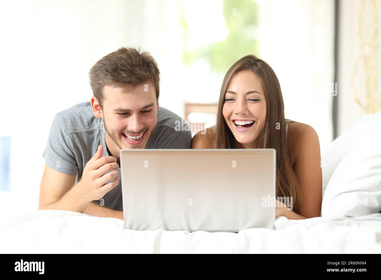 Front view portrait of a funny couple laughing watching laptop content ...