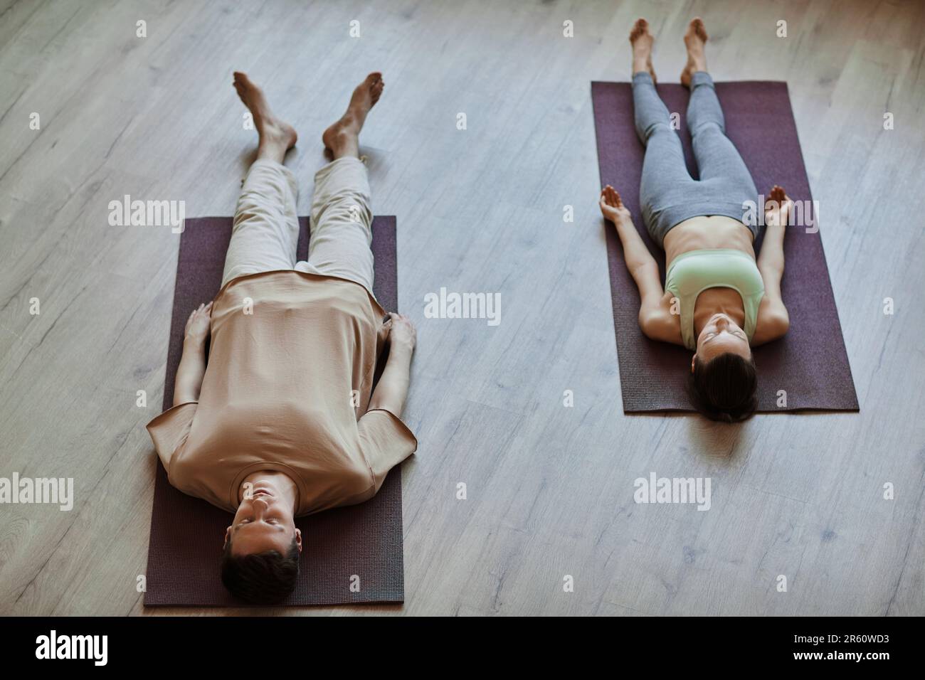 Top view at two young people lying down on floor in meditation with ...
