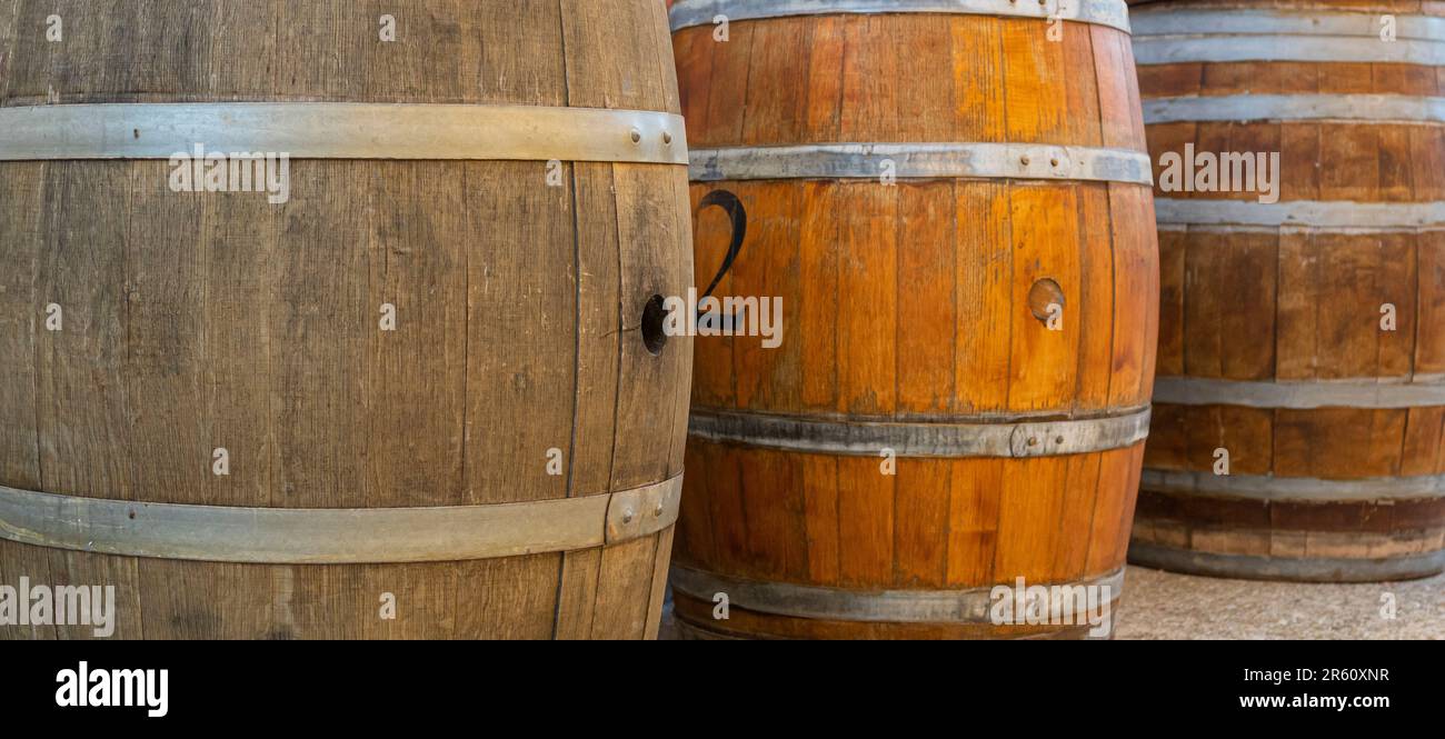 A close-up image of multiple wooden wine barrels with metal rings and ...