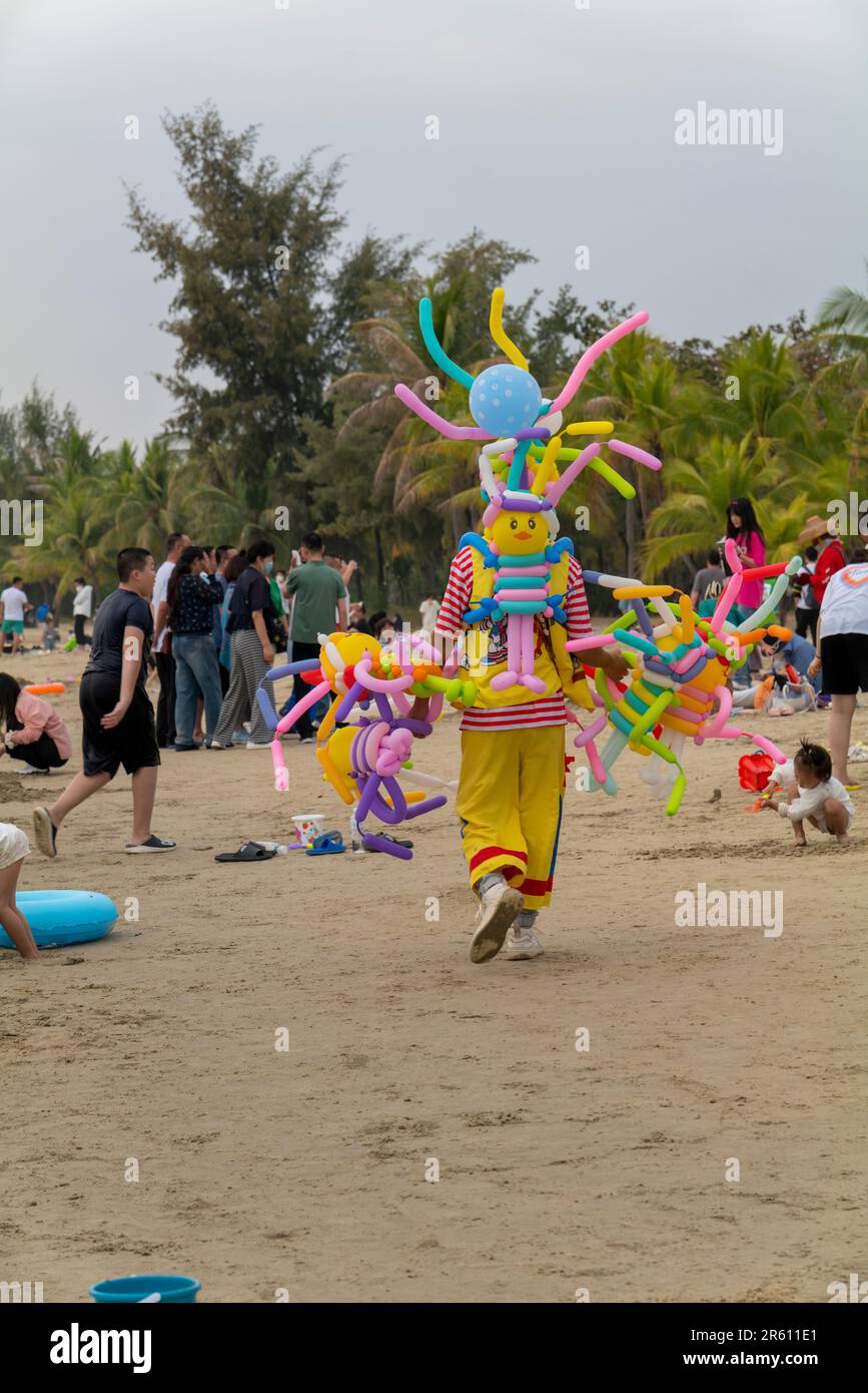 An adult male clown wearing a tall yellow and red striped hat stands ...