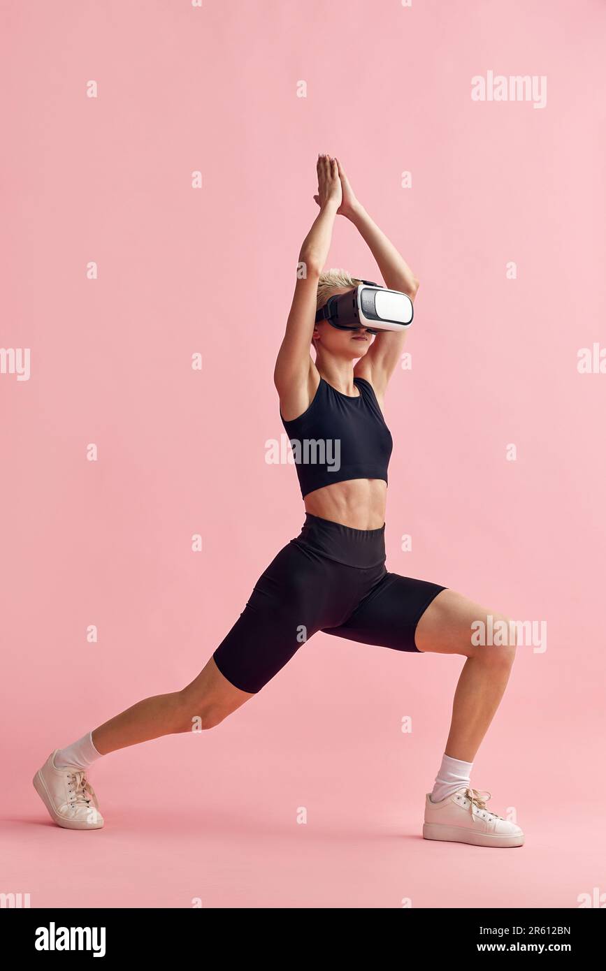 Portrait of young girl in black sportswear, wearing VR glasses and ...