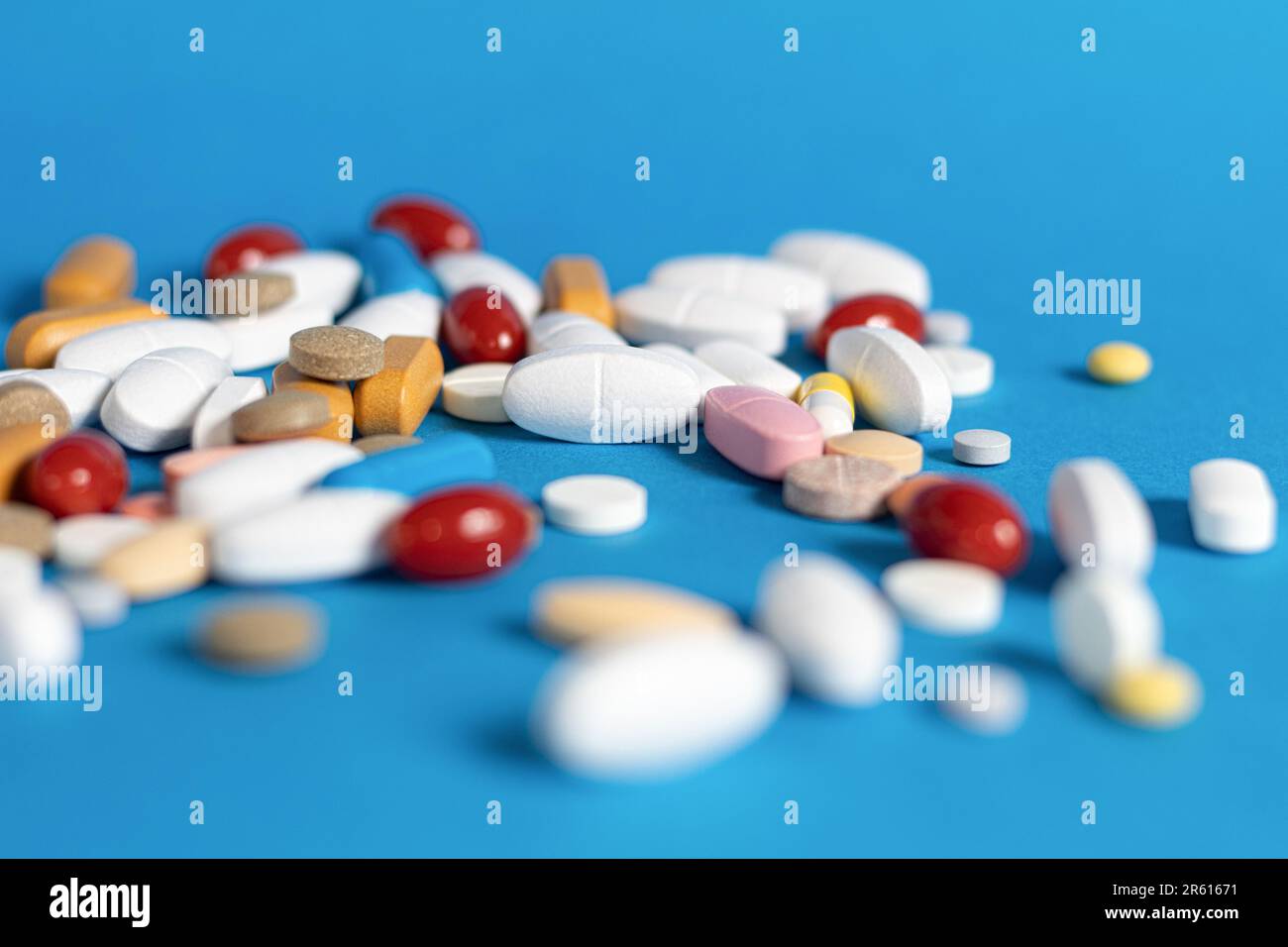 Many pills, different shapes and different colors on a blue background ...