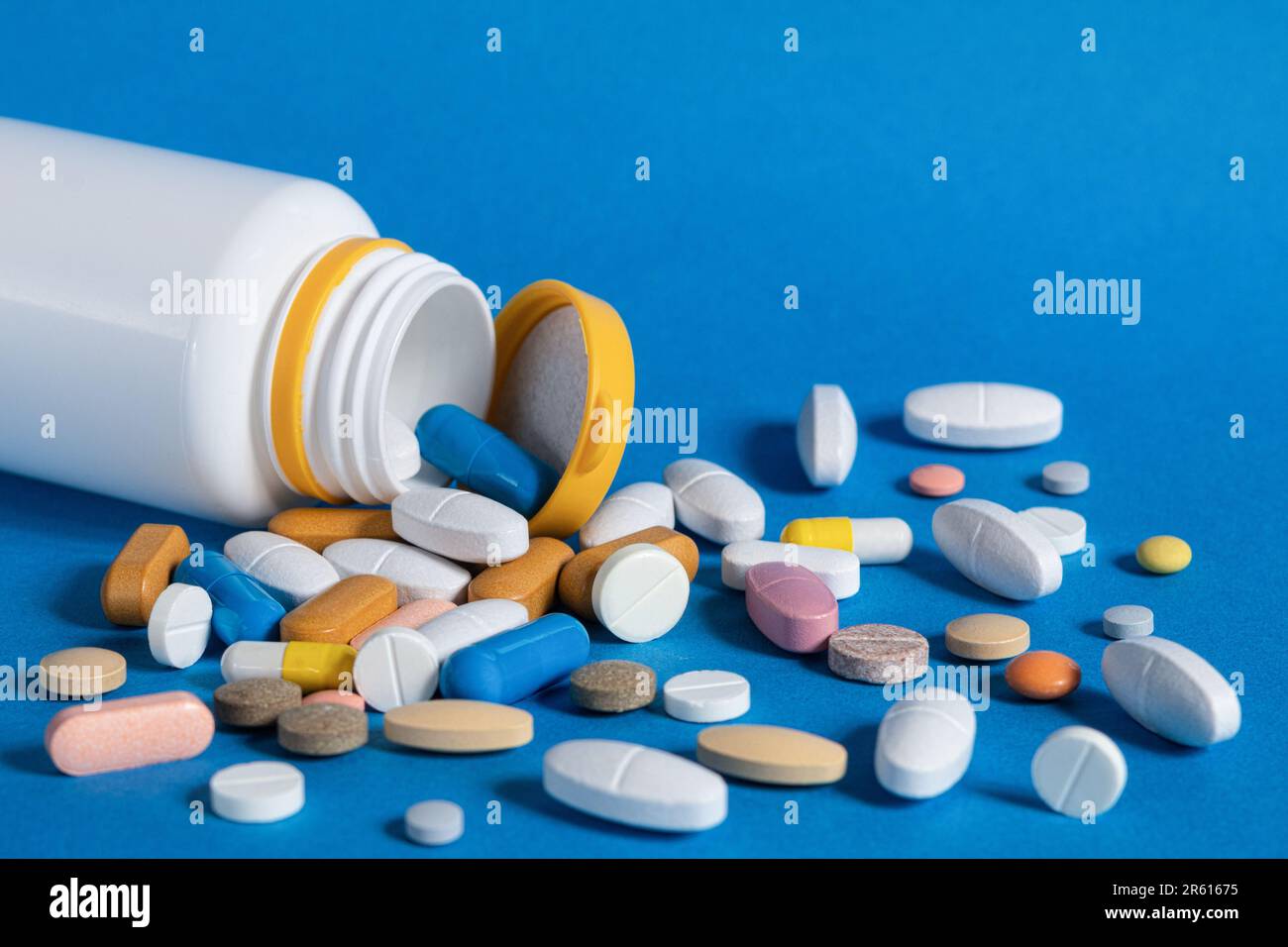 Many pills, different shapes and different colors on a blue background ...