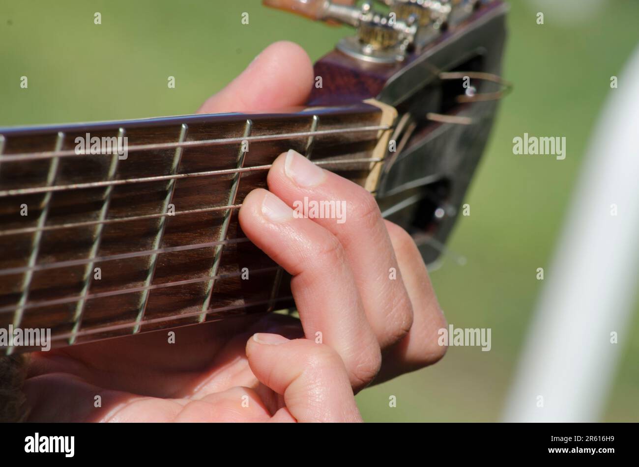 A young male musician is strumming an acoustic guitar in an outdoor ...