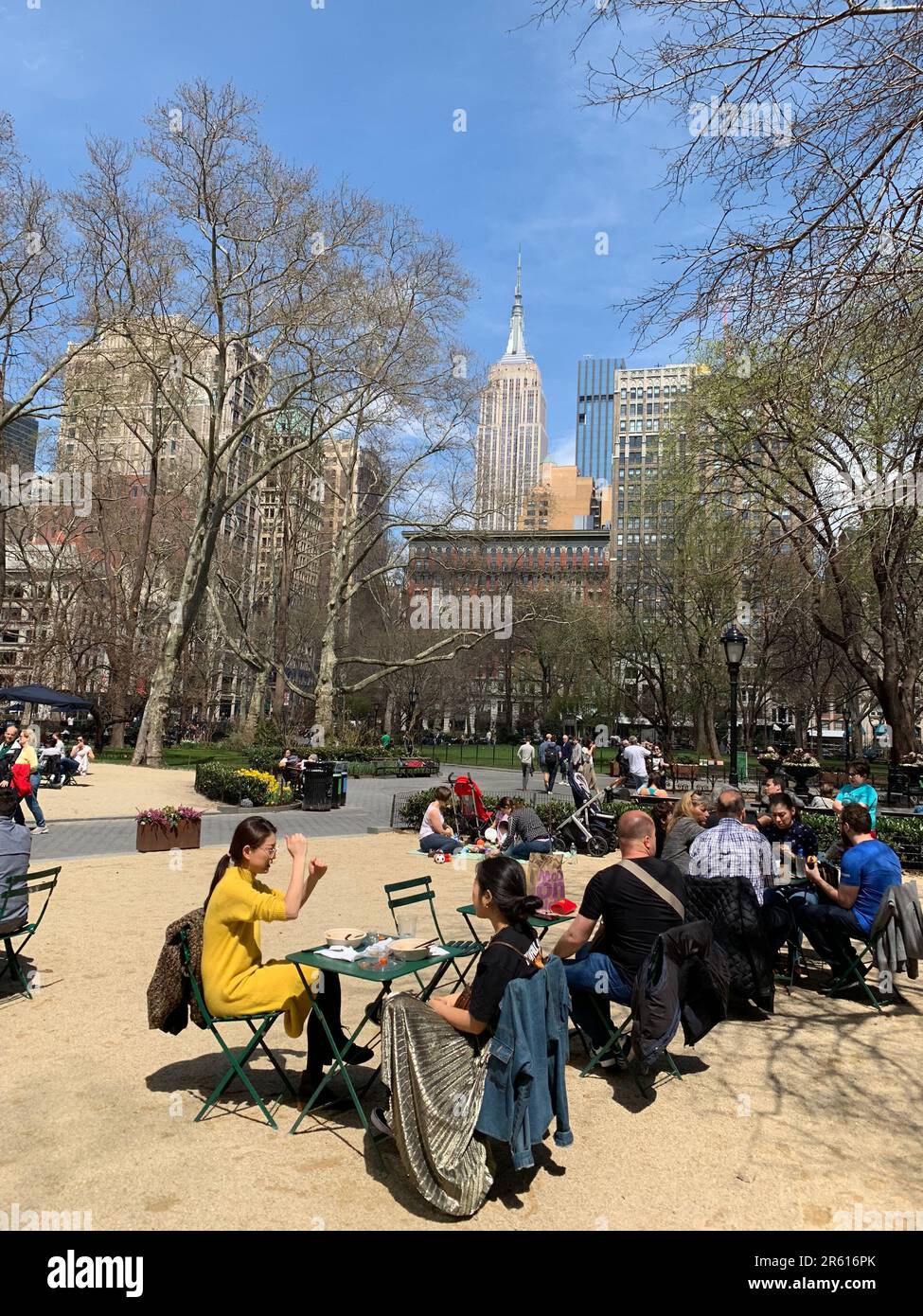 Friends enjoy a sunny spring day talking and eating at an outdoor cafe ...