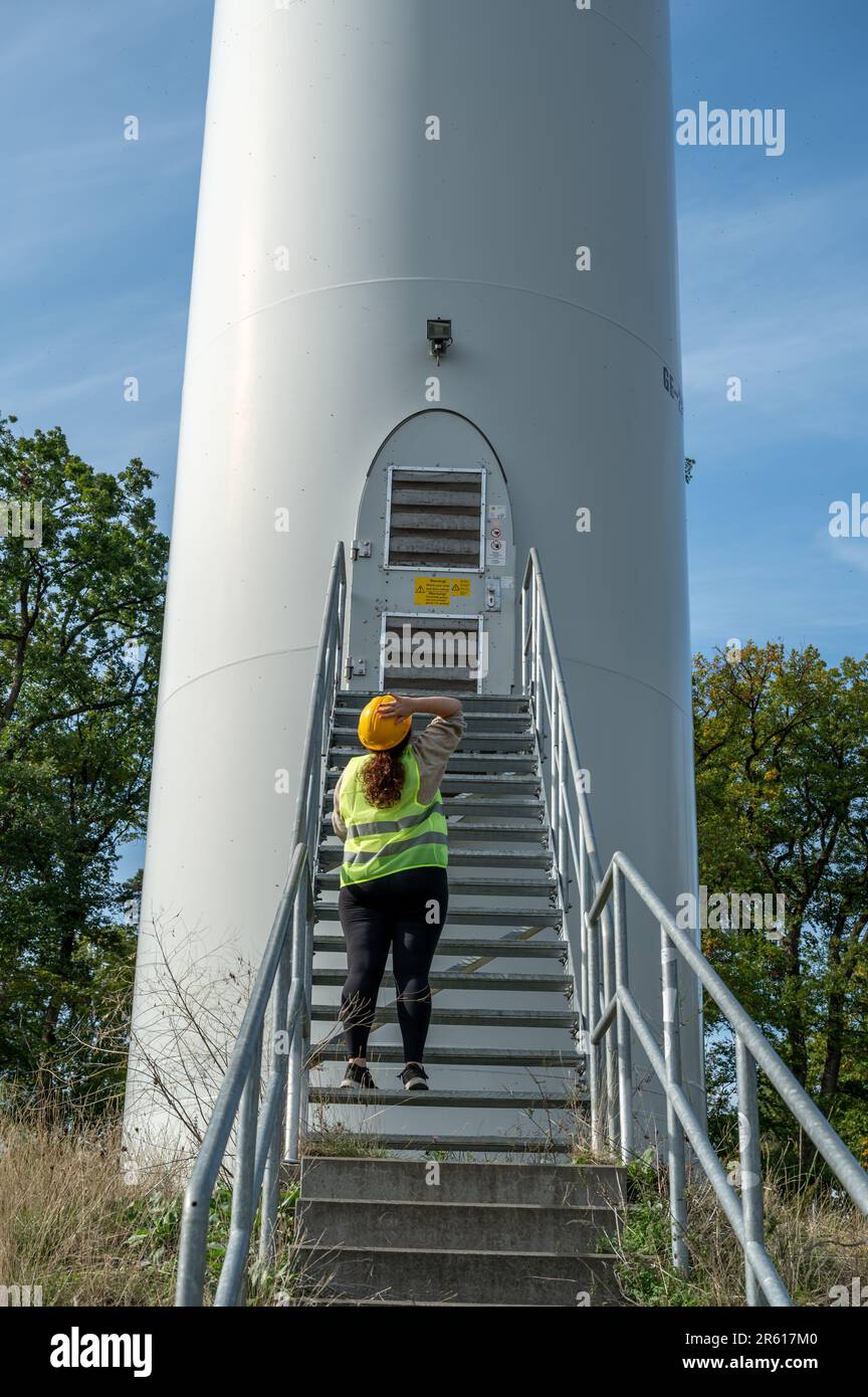 A female engineer ascending a flight of stairs leading to a tall tower ...