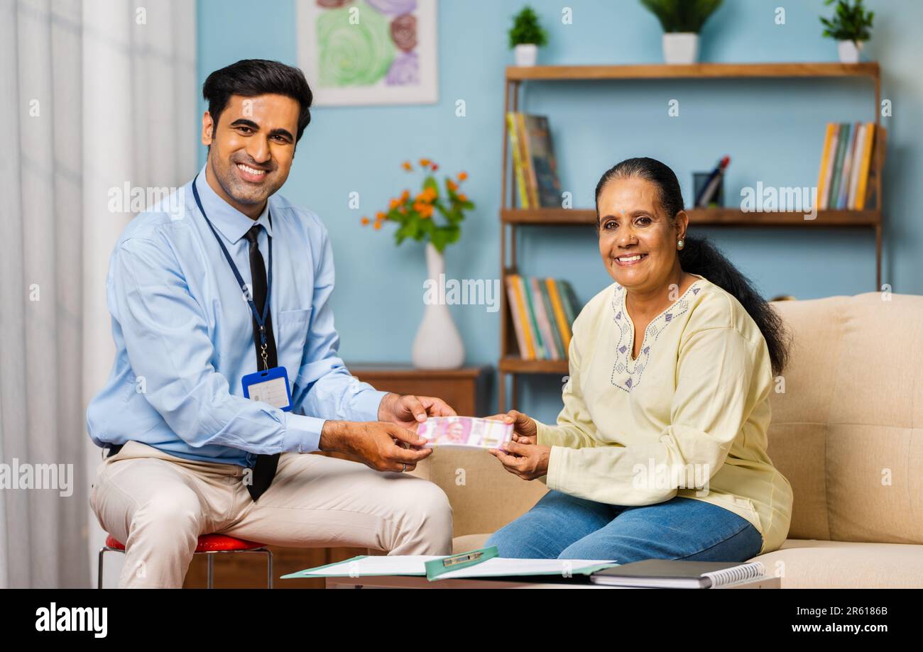 Happy smiling indian banker giving money to senior woman by looking at ...