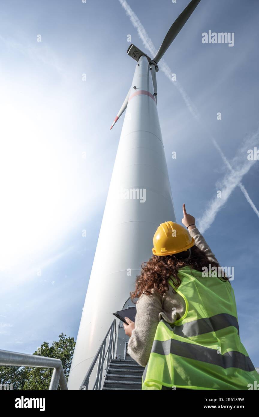 A female professional wearing a hard hat standing and pointing to a ...