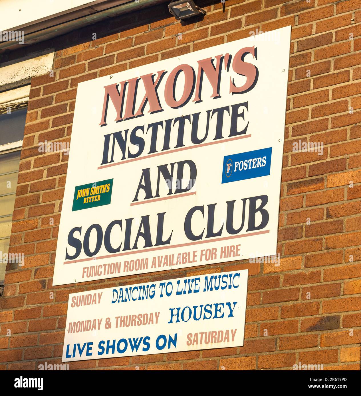 A sign hanging on a brick wall with the text 'Nixon's Institute and ...