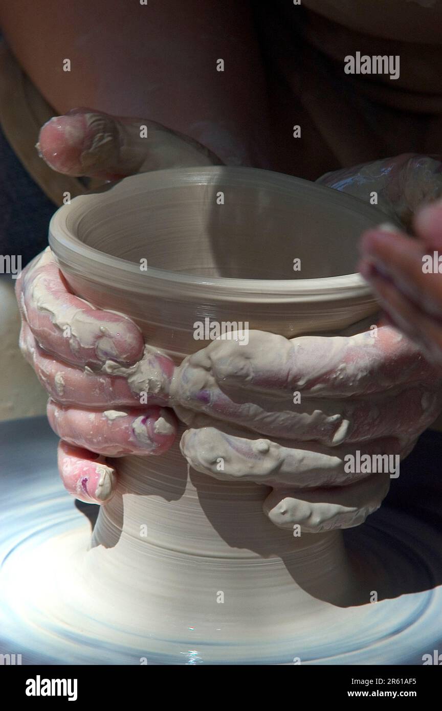 A person is engaged in a pottery craft, using a wheel and clay to form ...