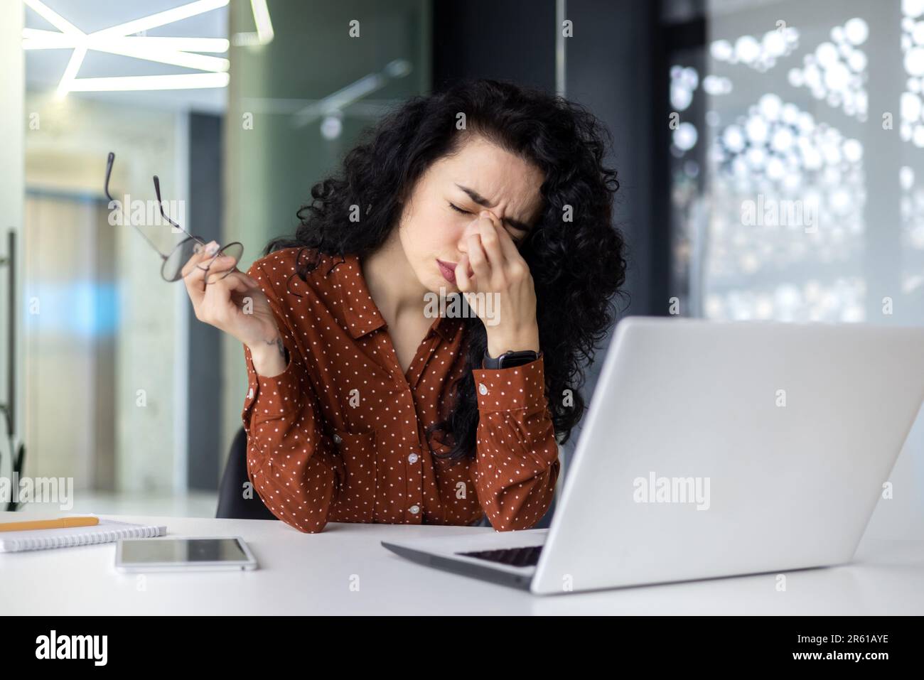 Overtired hispanic woman at work, business woman in glasses holding ...