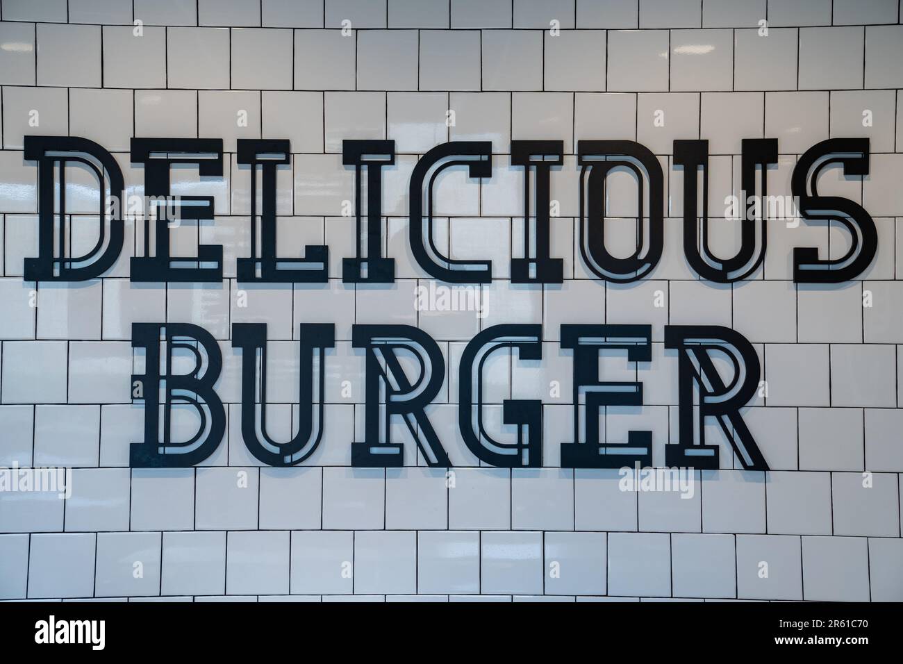 Delicious Burger text on a while tiled wall Stock Photo - Alamy