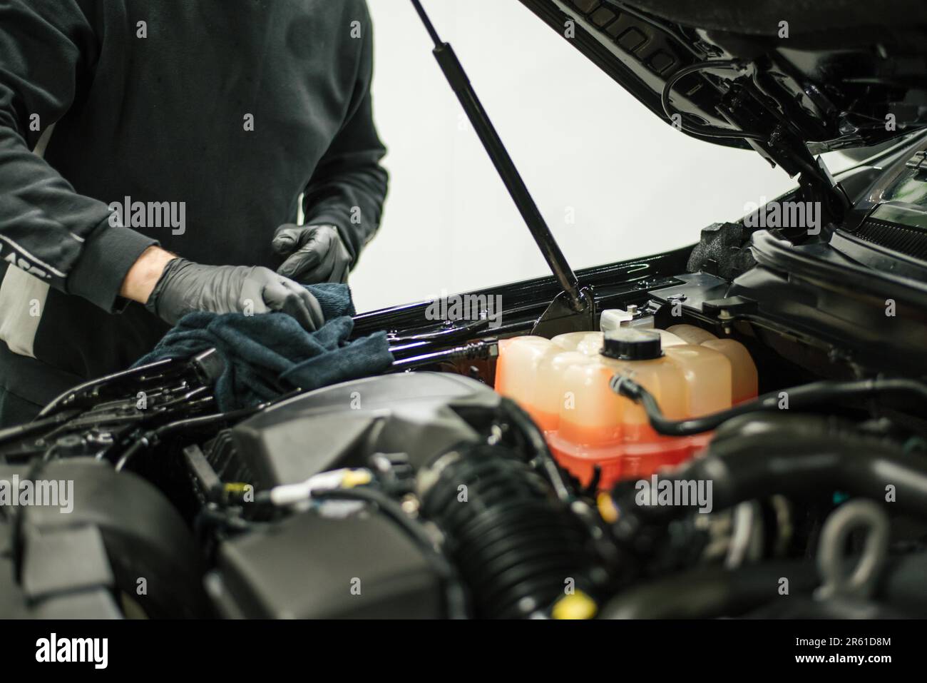 A mechanic standing in front of a car, its hood open to reveal the ...