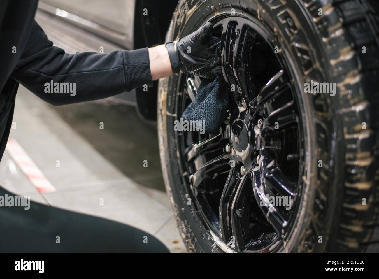 A closeup of a mechanic performing a detailed tire cleaning on a car's ...
