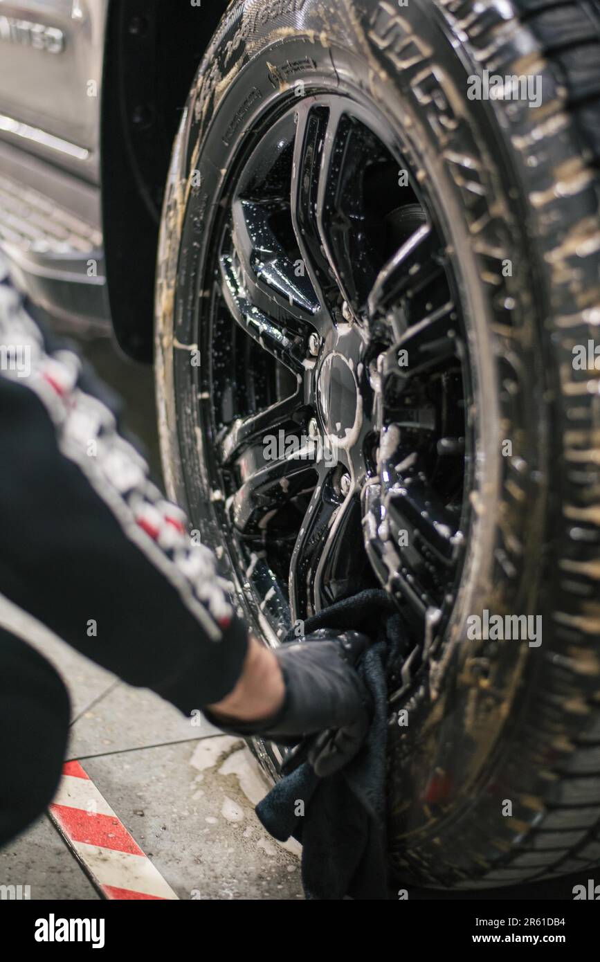 A closeup of a mechanic performing a detailed tire cleaning on a car's ...