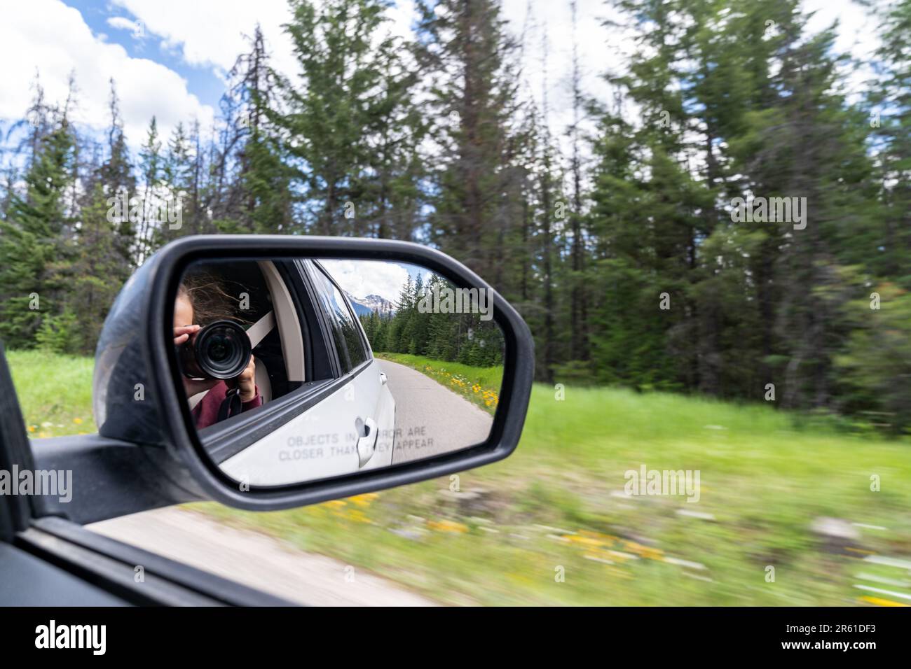 Tourist takes a photo through the rear view mirror of a car, taken in ...