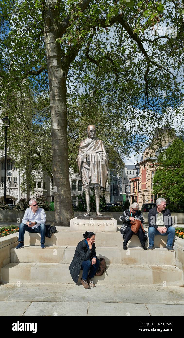 Tourists sit on the steps below the statue, of Mahatma Gandhi, in ...