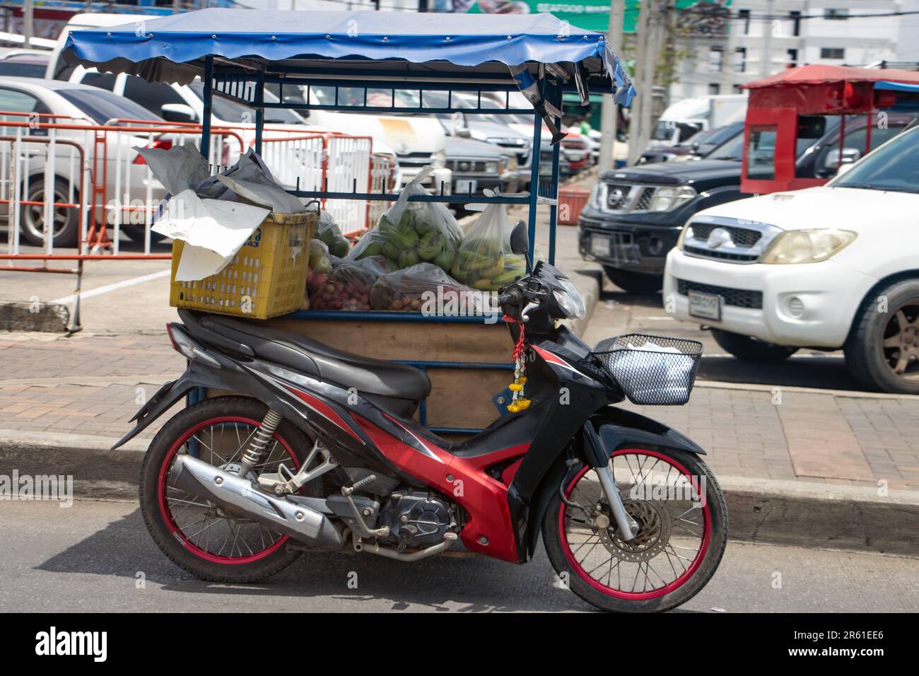 A motorcycle with a sidecar loaded with bags of fresh fruit is parked ...