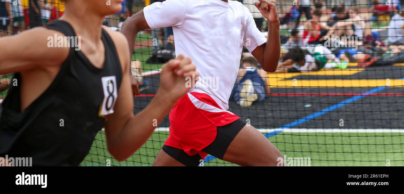 Side view of boys running in a sprint race next to a black safety net ...