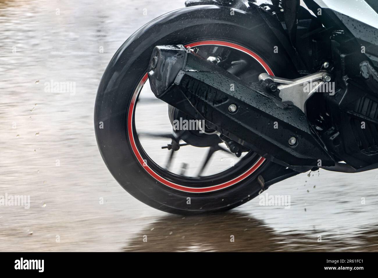 The rear wheel of a motorbike driving in the rain on a wet road Stock ...