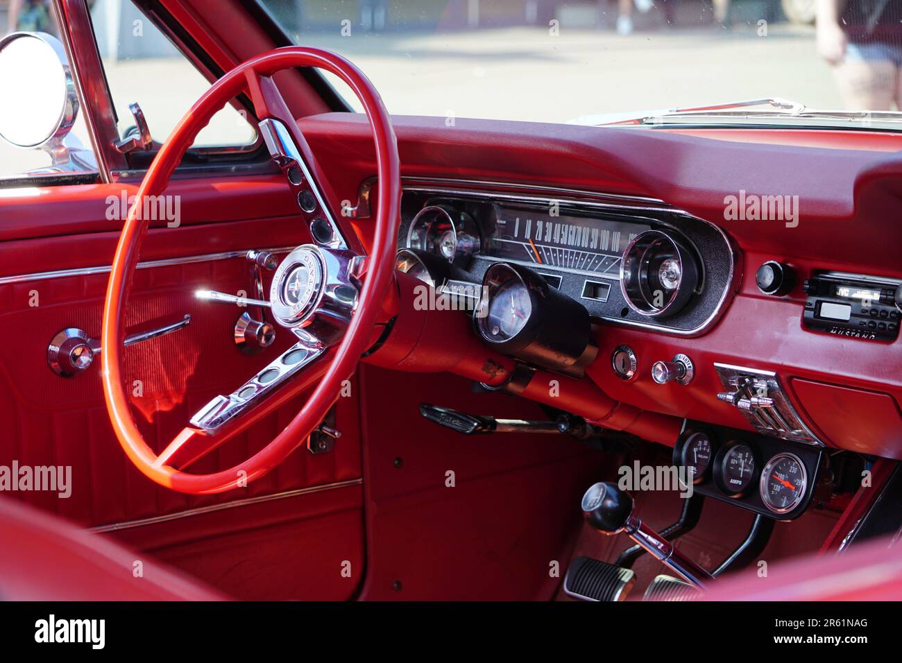 A red car interior with a steering wheel and a set of gauges visible ...