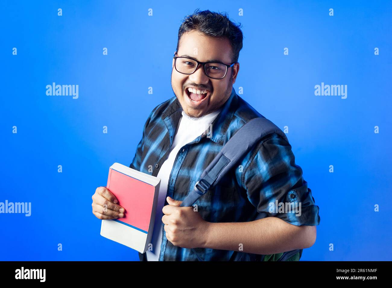 overweight collage student with big smile holding book in blue ...