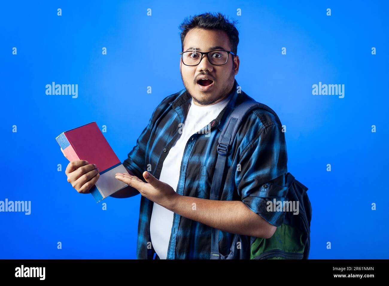 shocking expression of a student standing against blue background Stock ...