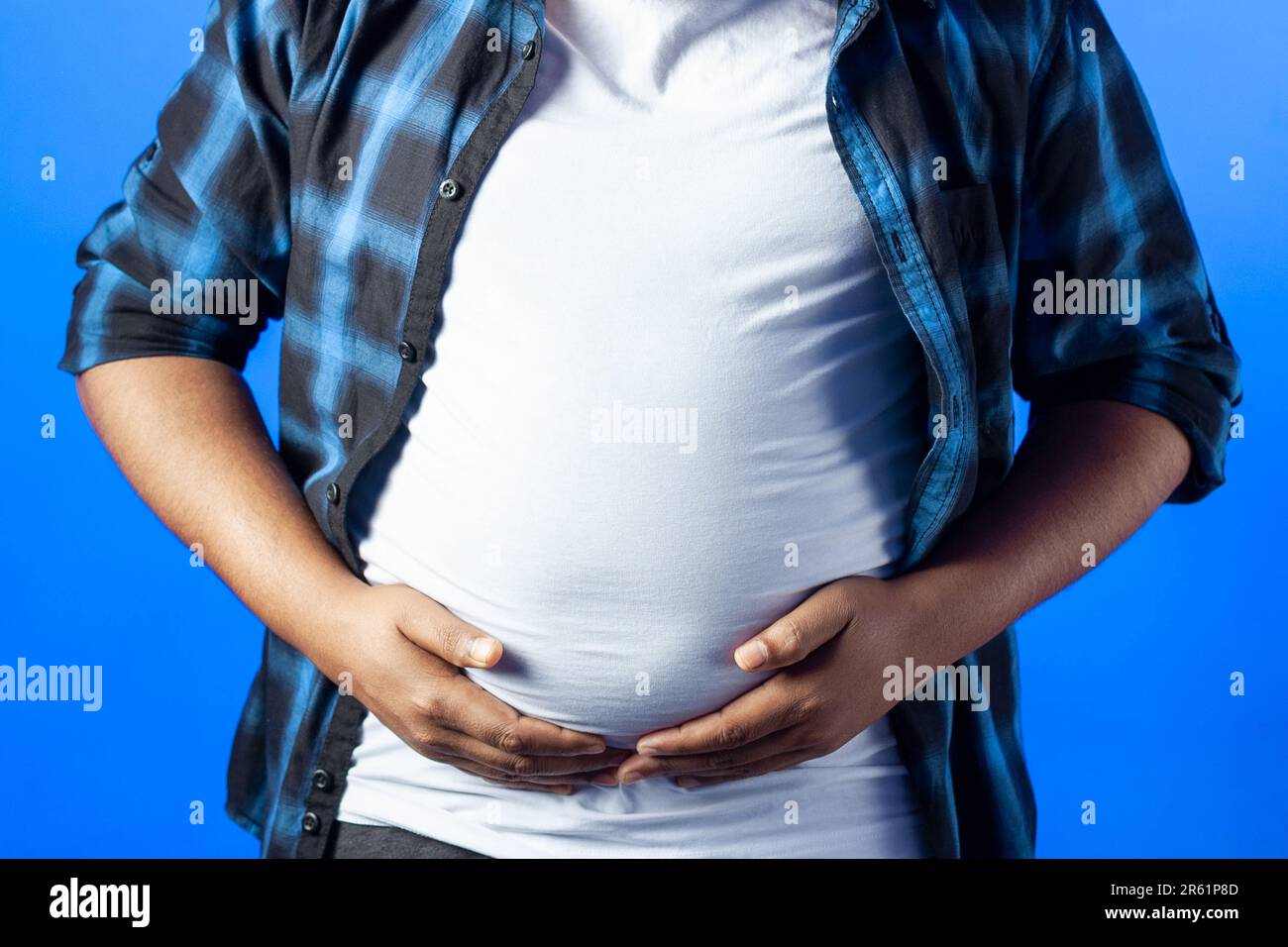 portrait of an Indian guy showing his fat on the stomach, isolated on ...