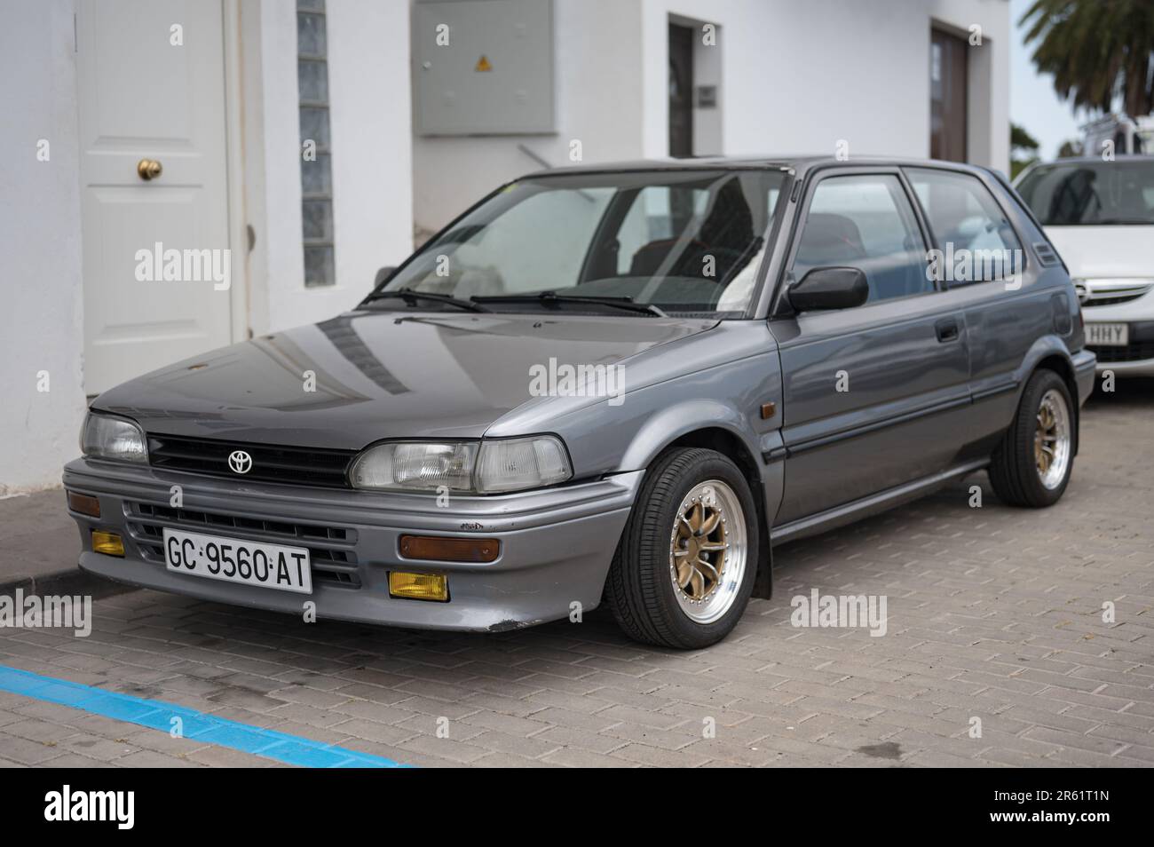 A classic Japanese car, the small Toyota Corolla XL EE90 in gray color parked in the street ...