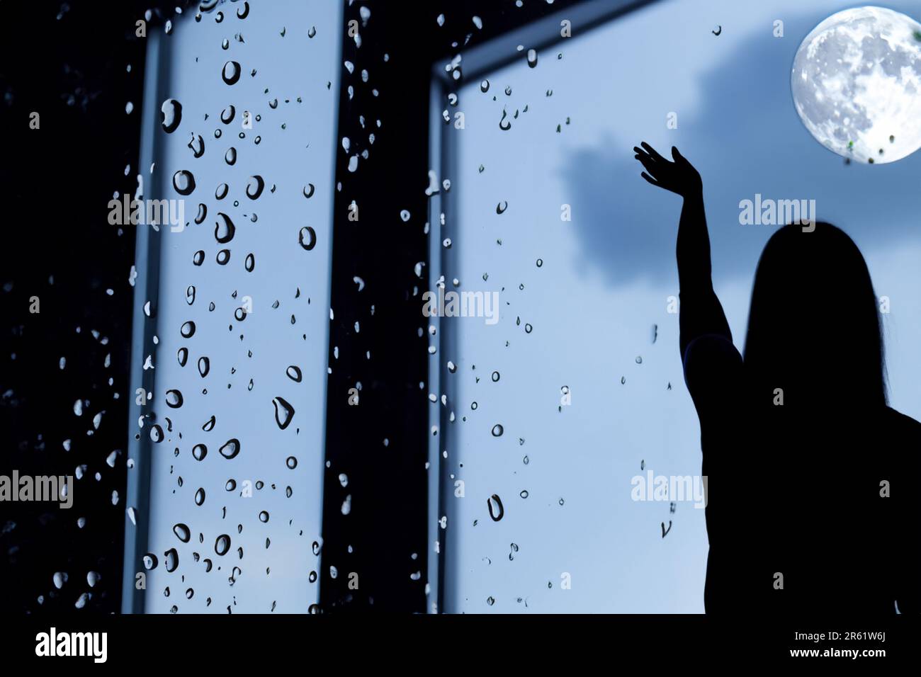 Silhouette of a woman reaching for the moon over a hi-res stock ...