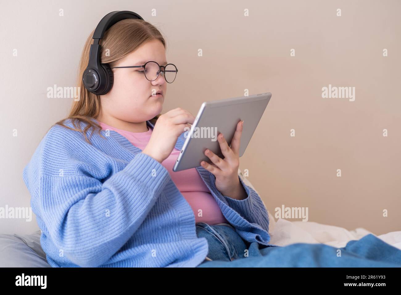 Relaxed teen girl in headphones completing online tasks on school ...