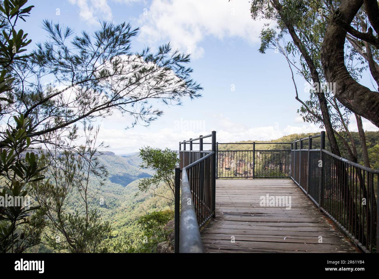 A wooden boardwalk with a handrail overlooks a scenic landscape ...