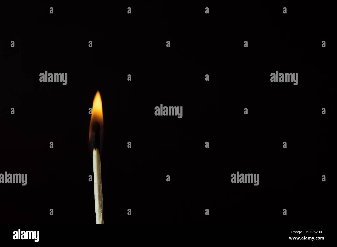 A single matchstick emitting a bright orange flame in a dark room Stock ...