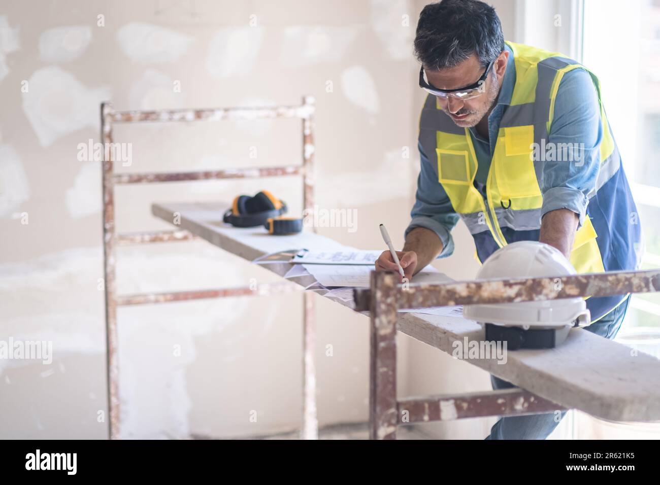 Focused architect writing notes on project documentation stands near ...