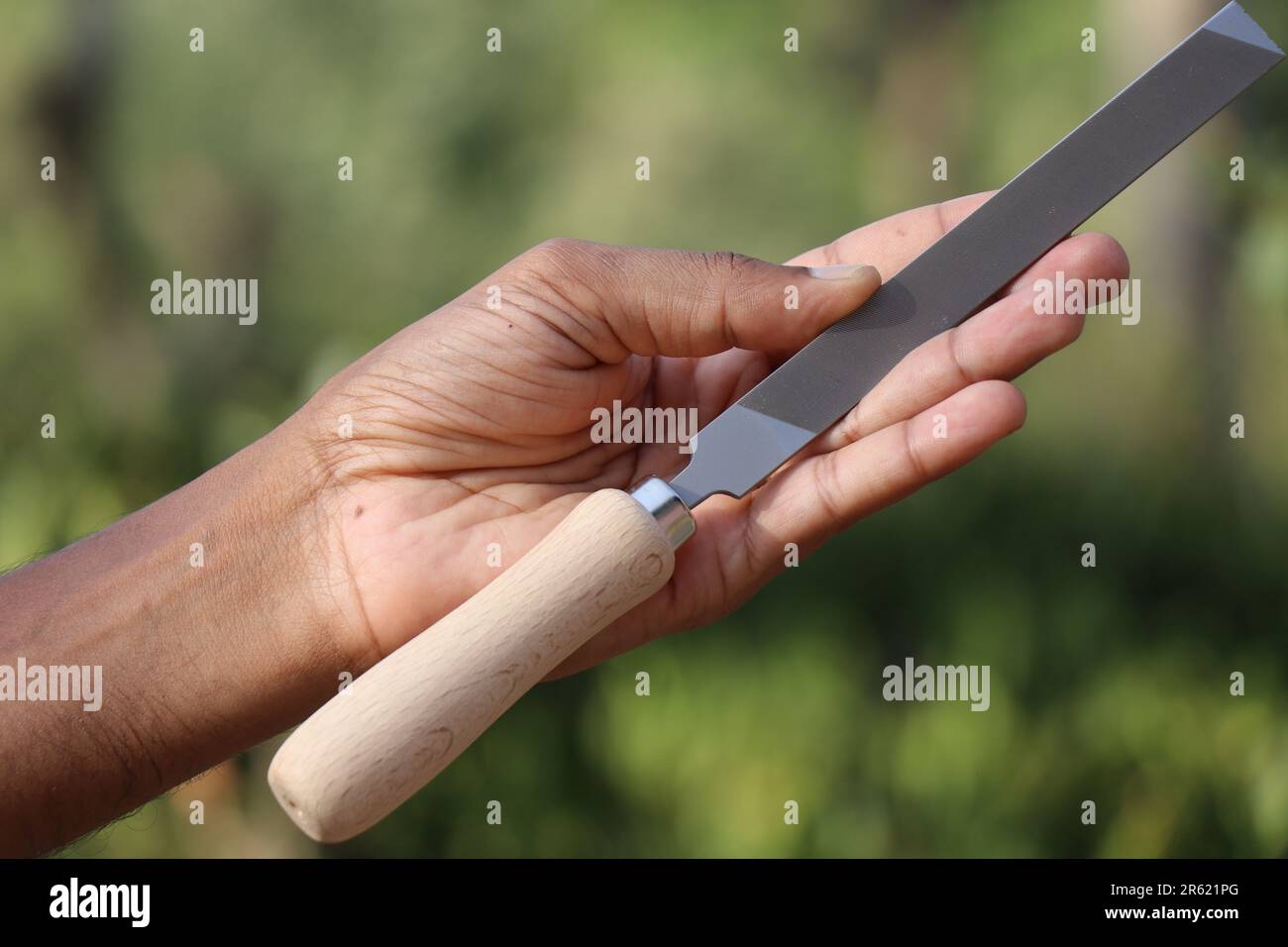 The iron file held in the hand on a nature background Stock Photo - Alamy