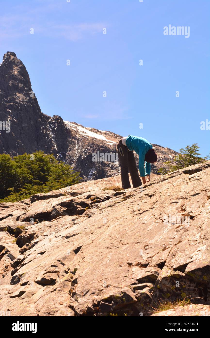 An adult person is doing exercise on a steep rocky mountain peak Stock ...
