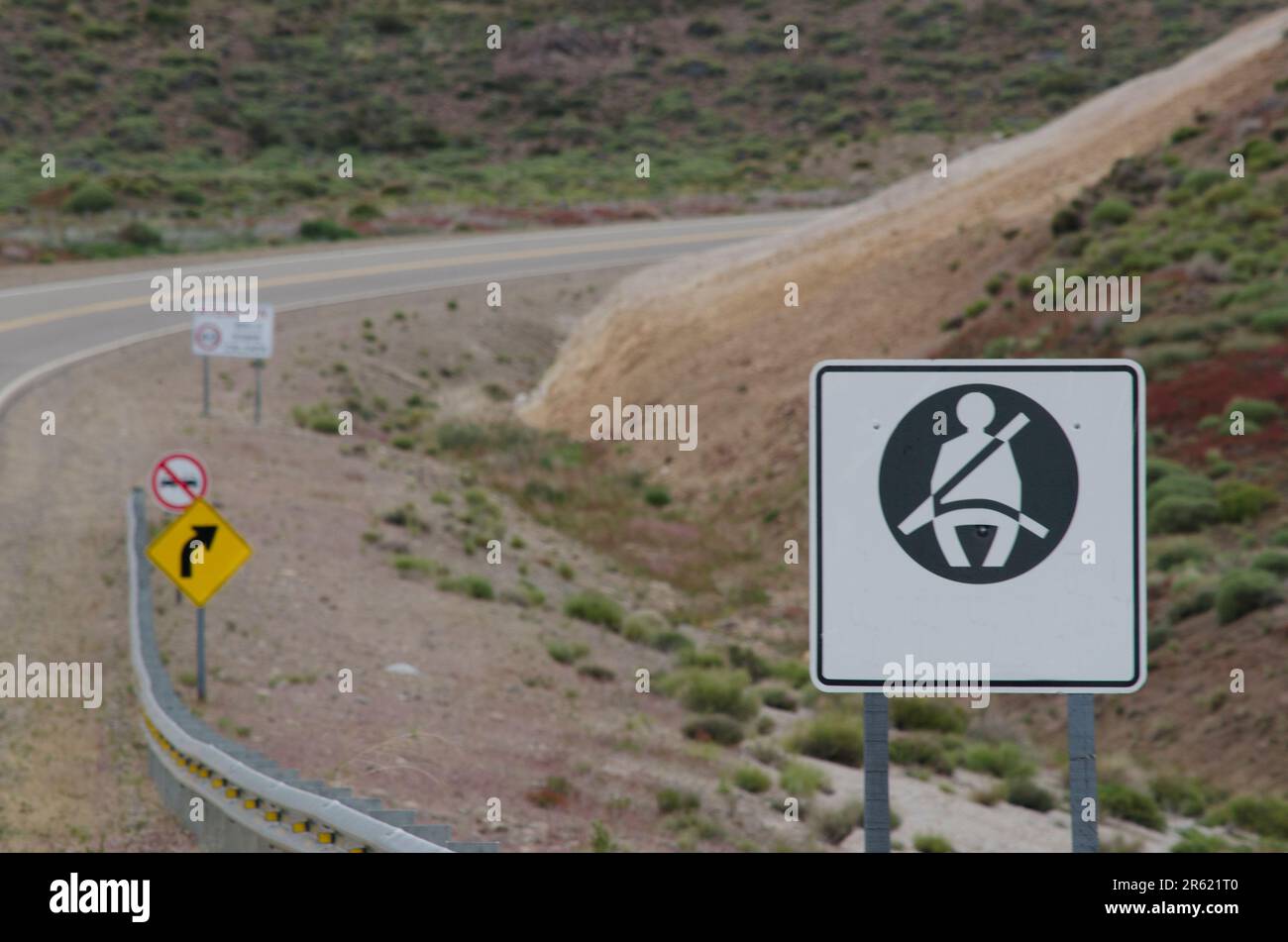 A cluster of road signs located on the side of a dusty road in a desert ...