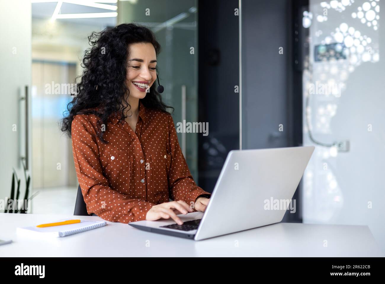Smiling hispanic businesswoman working inside office with laptop and ...