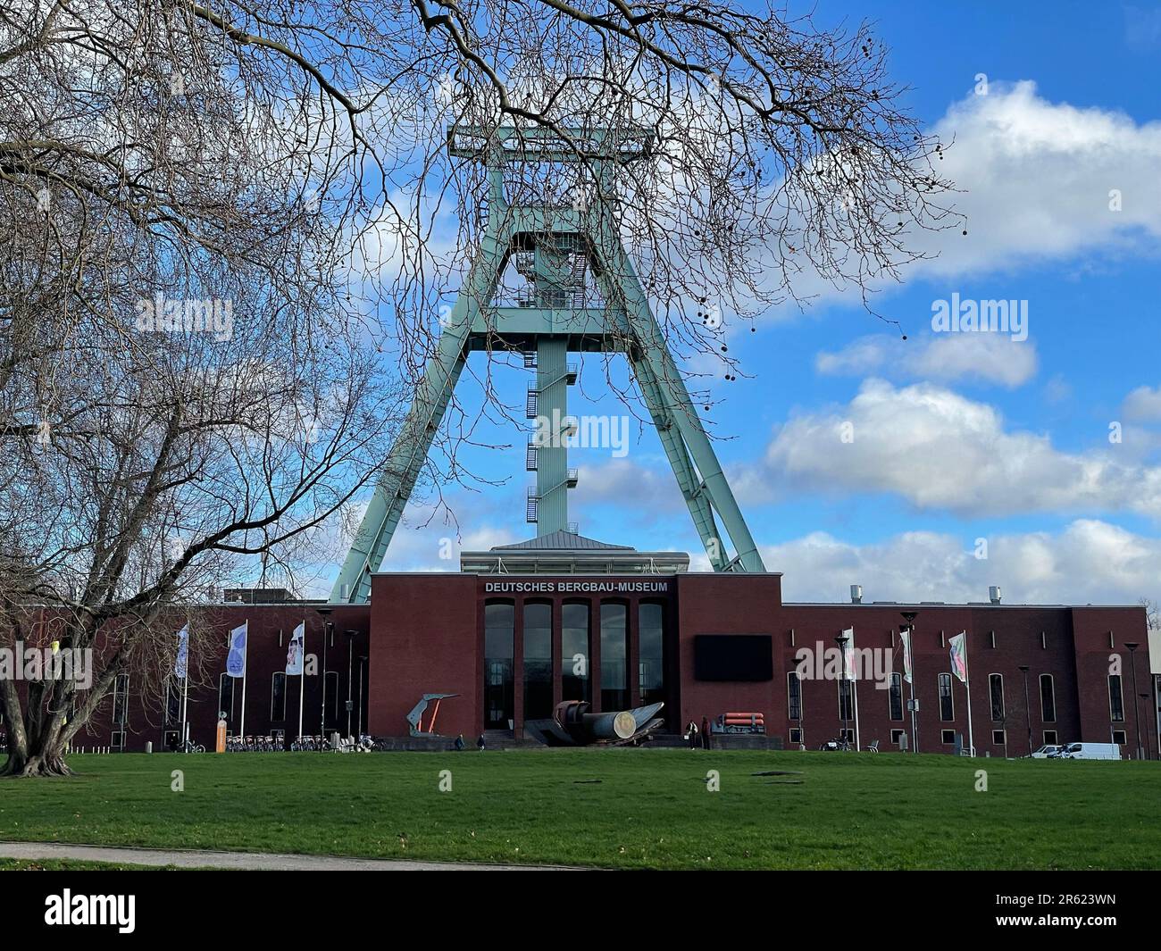 A classic clock tower in a green park setting with a tall building in ...