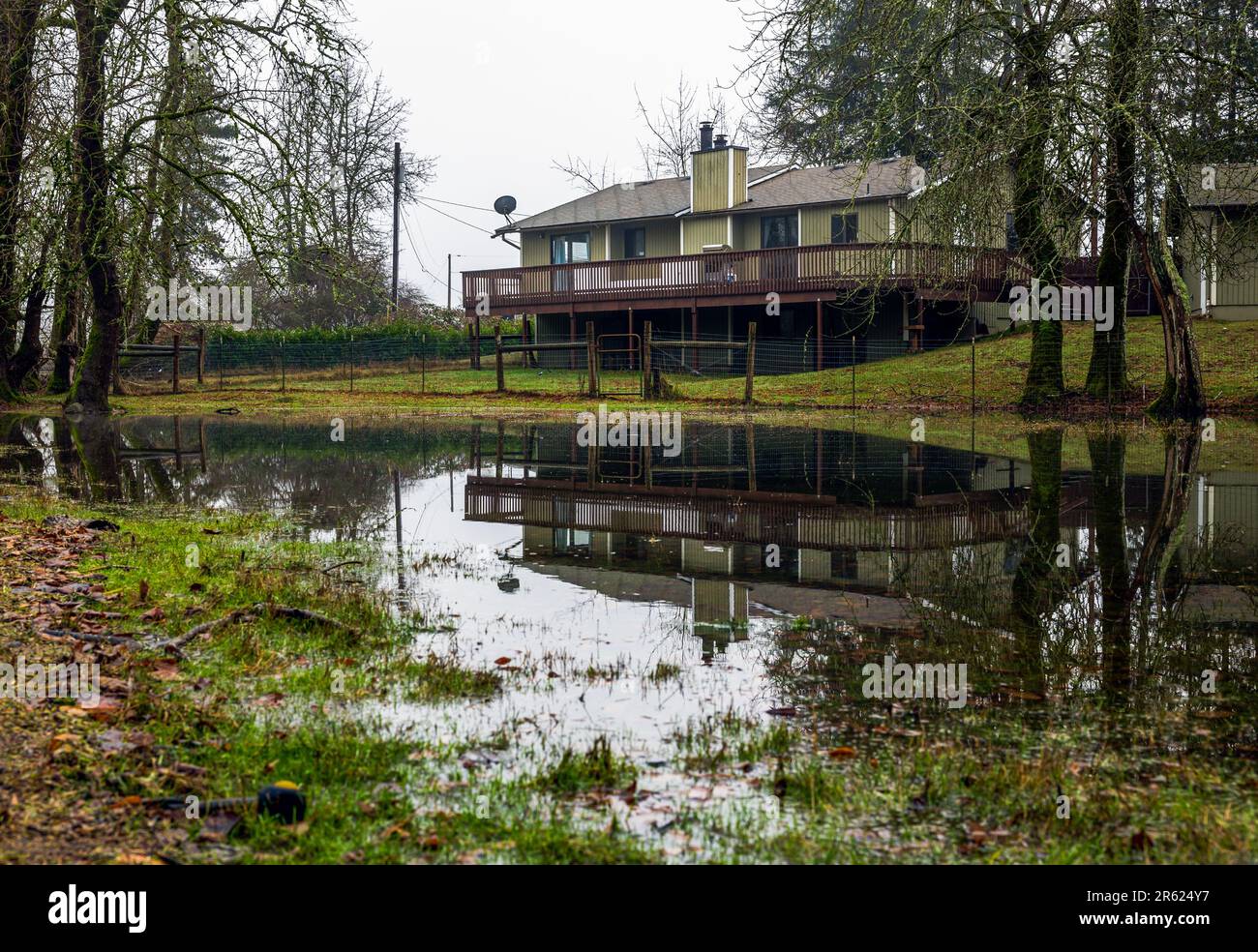 A tranquil scene featuring a house reflected in a still pond ...