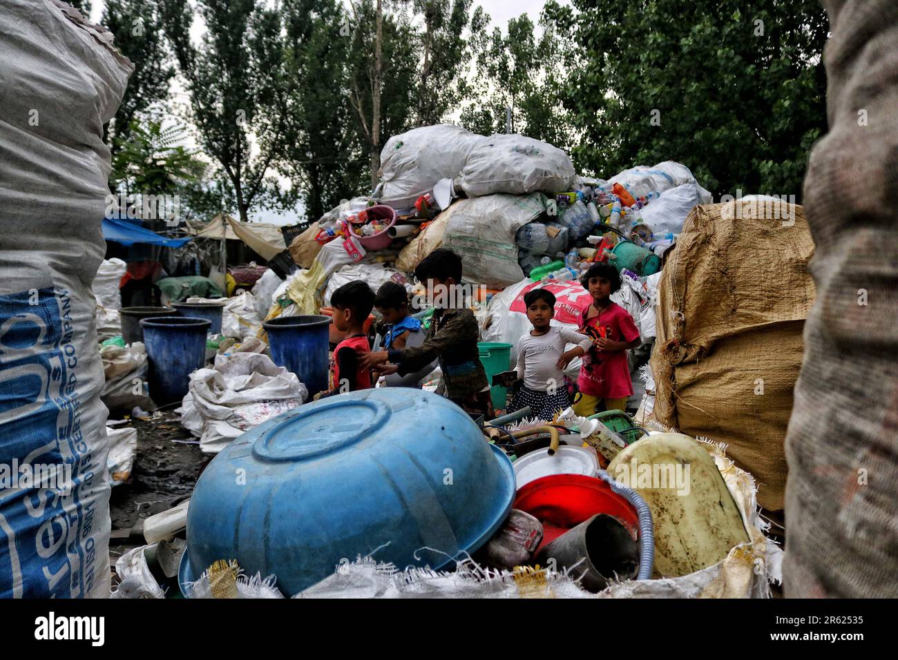 Srinagar Kashmir, India. 05th June, 2023. Children walk past plastic waste near a garbage dump ...