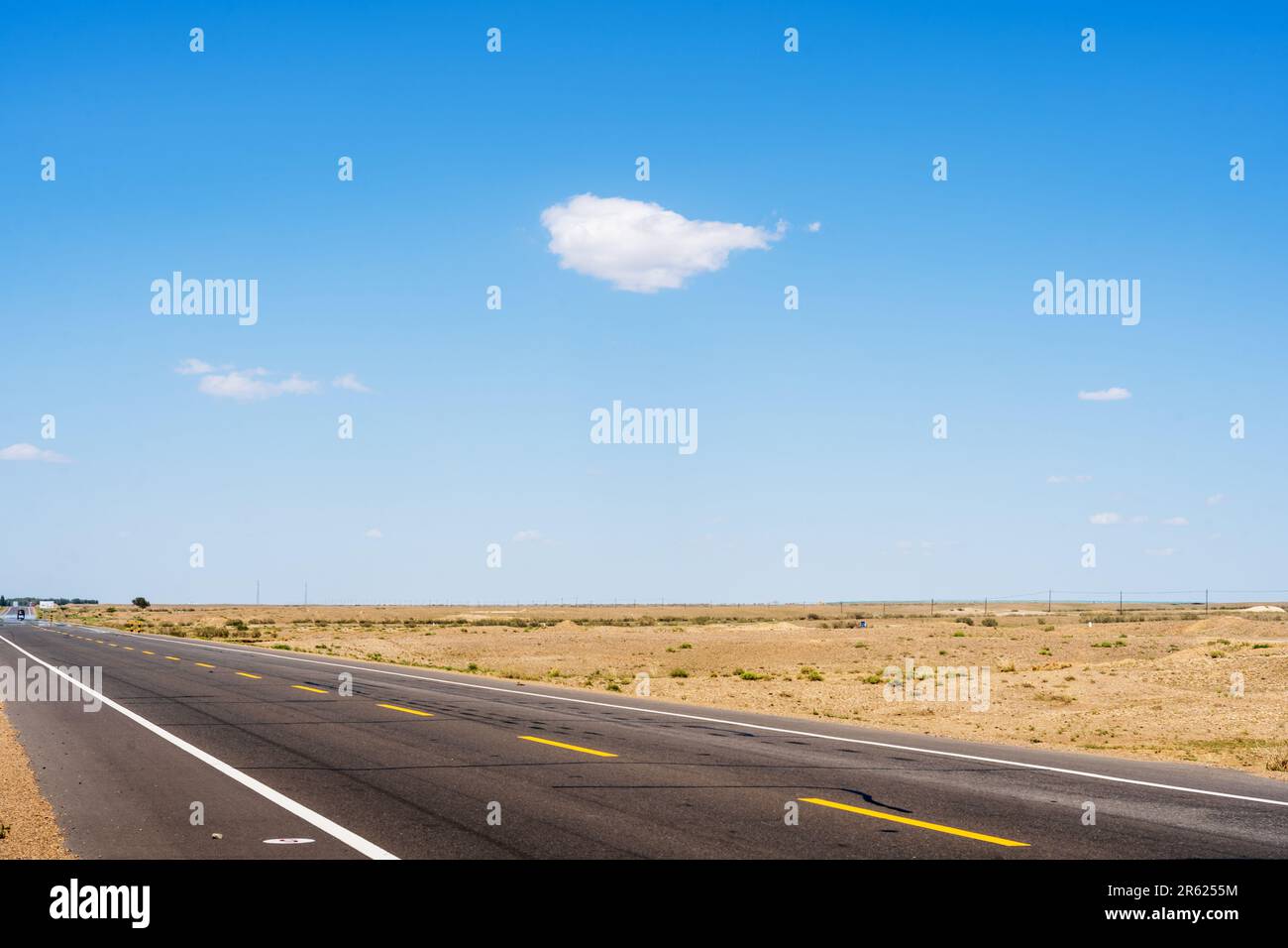 A winding asphalt road stretches out in the distance, while a white ...