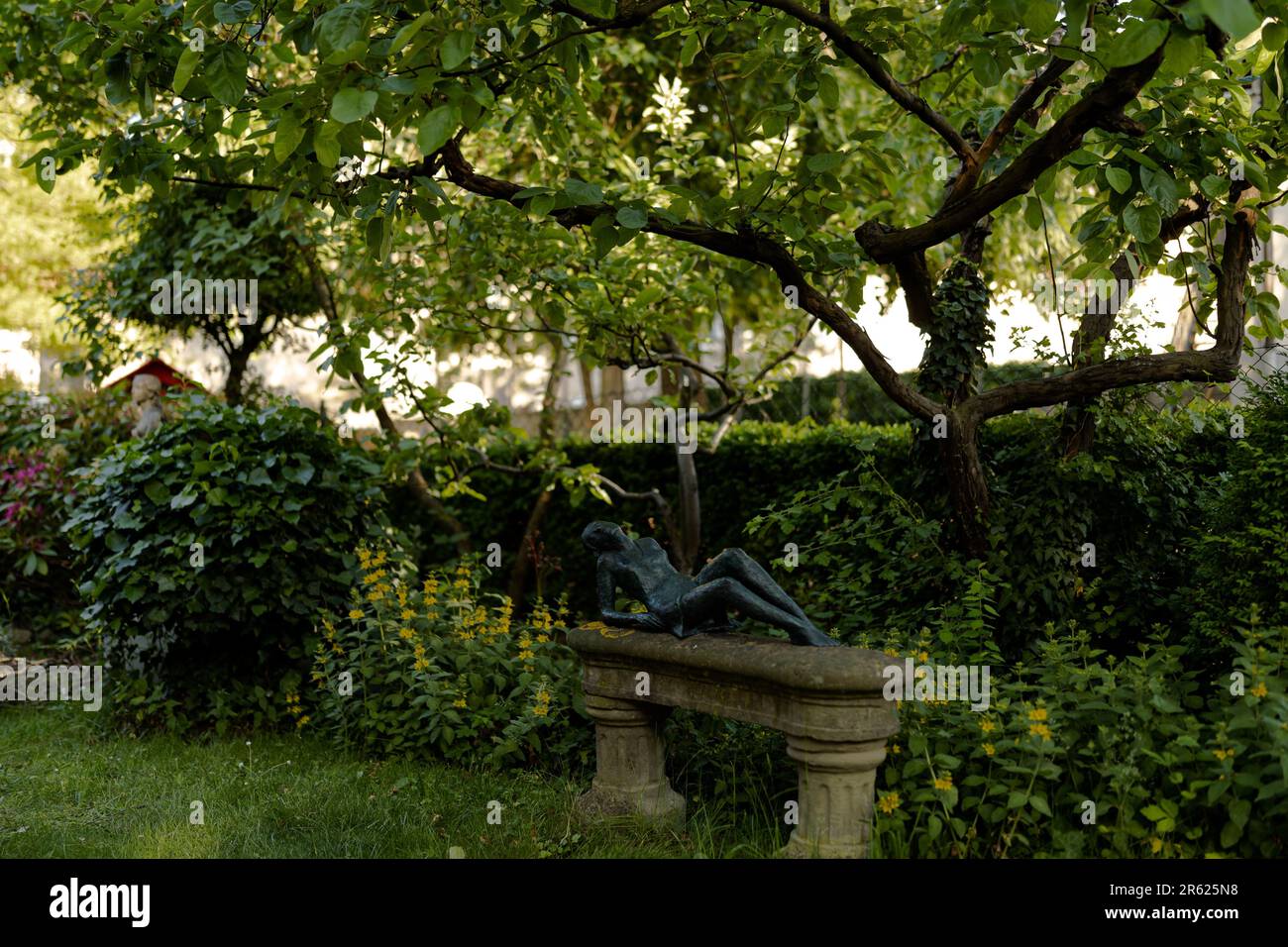 A majestic bronze statue of a reclining figure in a tranquil garden ...