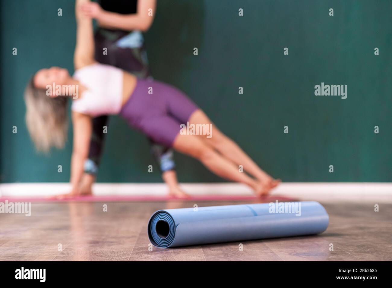 Gymnastic mat roll put on wooden floor against coach helping female ...