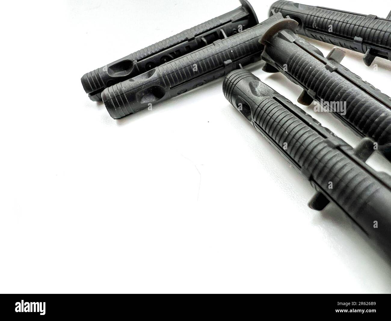A close-up image of four black rifles with rubber grips and black ...