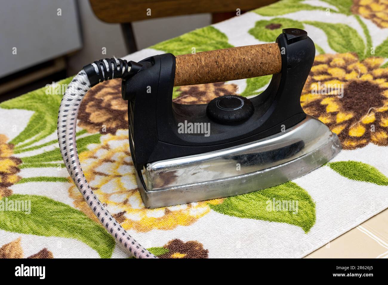 A close-up photo of a vintage iron on a floral patterned table cloth ...