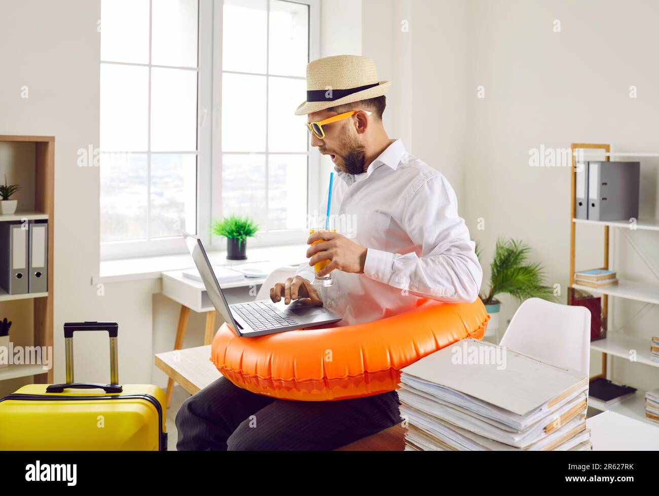 Funny man sitting at the desk of his workplace at office and booking ...
