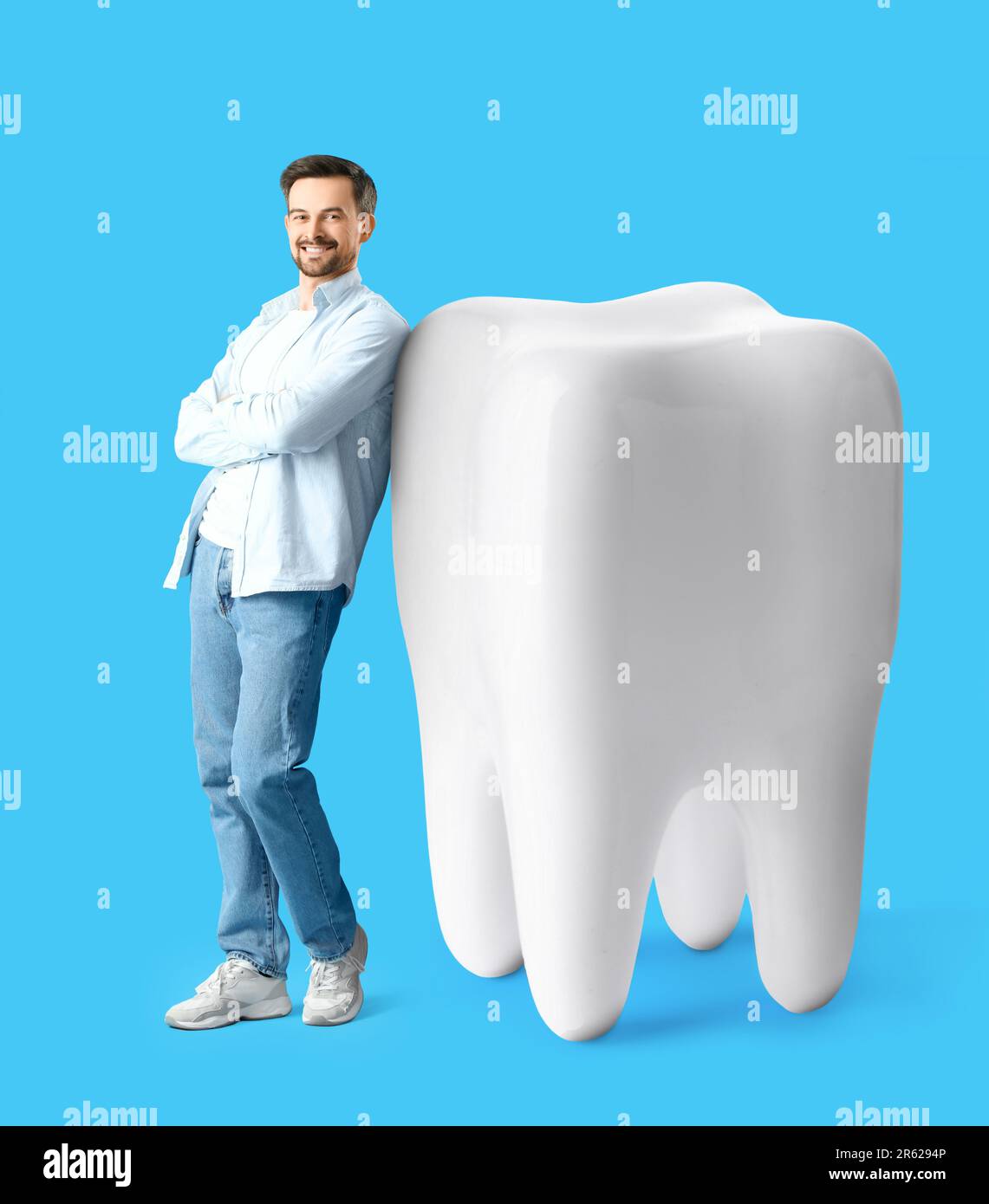 Happy man and big tooth on light blue background Stock Photo - Alamy